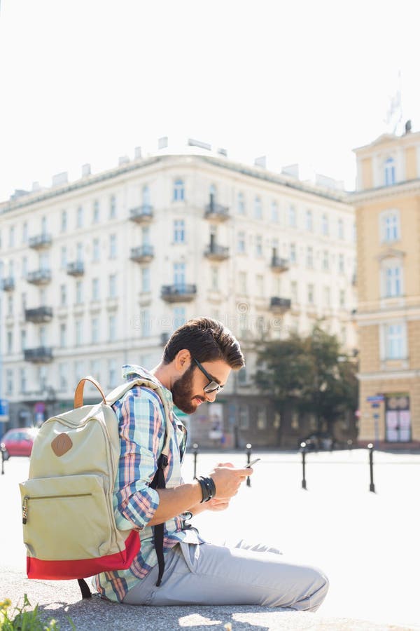 Side View of Man with Backpack Using Cell Phone in City on Sunny Day ...