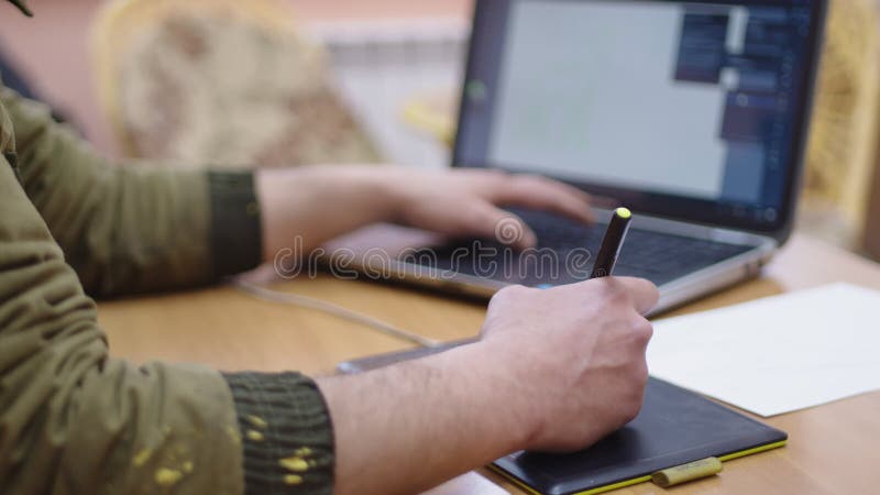 Side View of Man Draws and Works at a Computer Using a Graphics Tablet ...