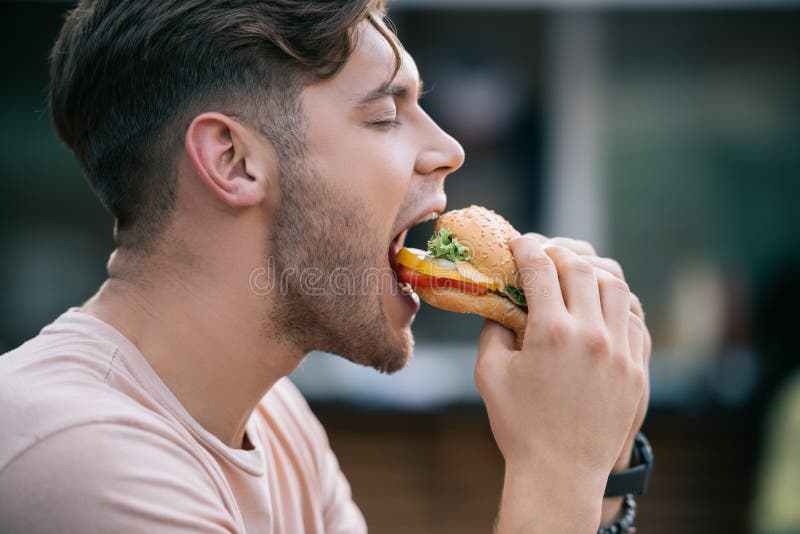 Side View of Man Eating Tasty Burger Stock Photo - Image of urban ...