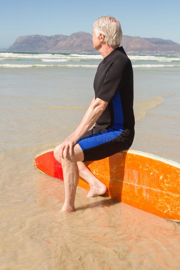 Side View of Man Sitting on Surfboard at Beach Stock Photo - Image of ...
