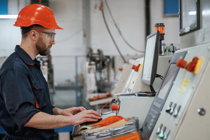 Side View, Operating the Machine. Factory Worker is Indoors with Hard ...