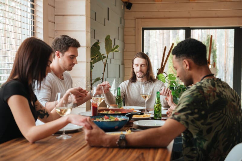 Side View Picture of a Group of Friends Praying Over Dinner Table Stock ...