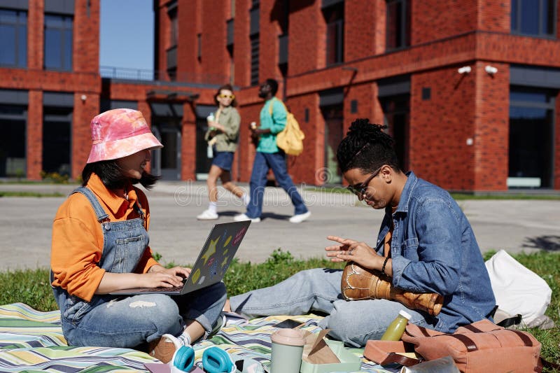 Two Young Students Studying Together Sitting on Grass in Sunlight Stock ...
