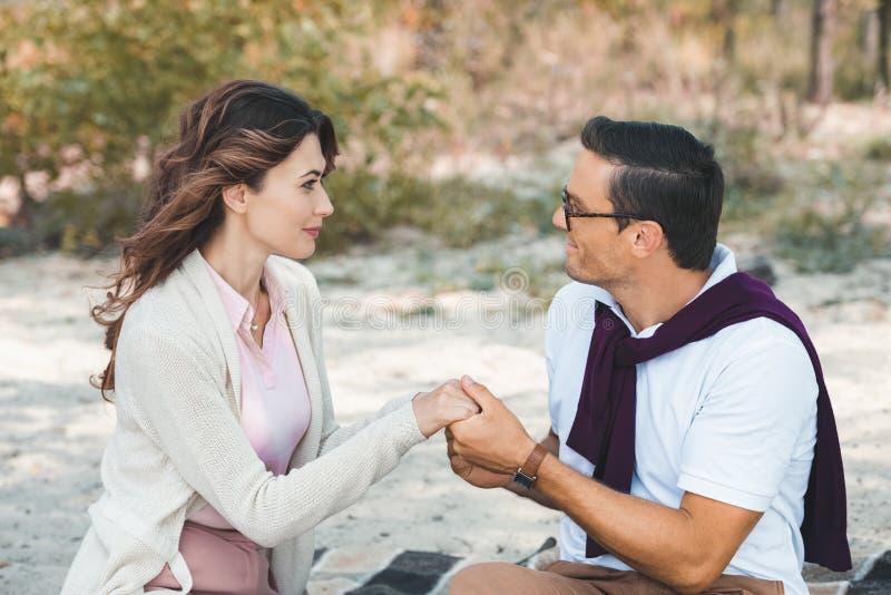 Side View of Romantic Couple Holding Hands while Resting on Blanket ...
