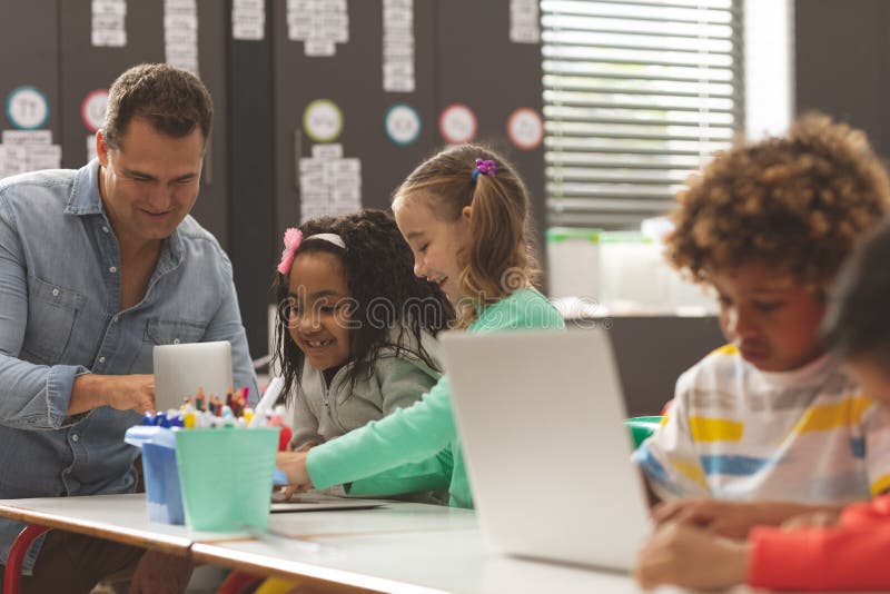School Boys Using Laptop in Classroom while Teacher Discussing with ...