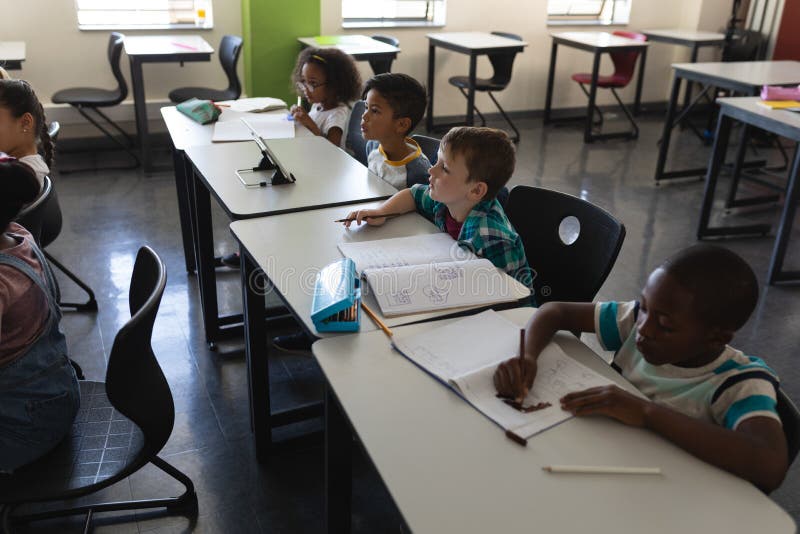Side View of Schoolkids Studying and Sitting at Desk in Classroom Stock ...