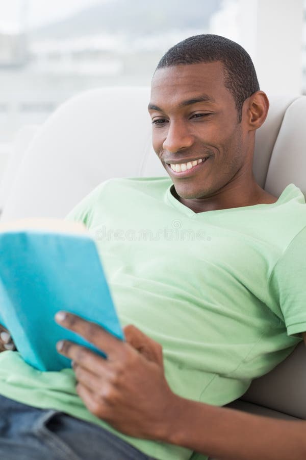 Side View of Smiling Afro Man Reading a Book on Sofa Stock Photo ...