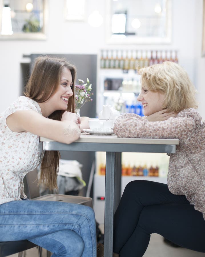 Side View of Smiling Young Female Friends Sitting at Cafe Table Stock ...