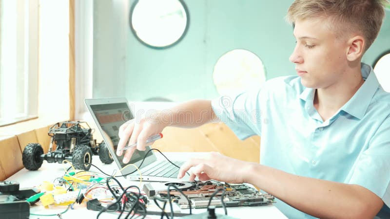 Side View of Student Looking at Laptop Screen and Fixing Board ...