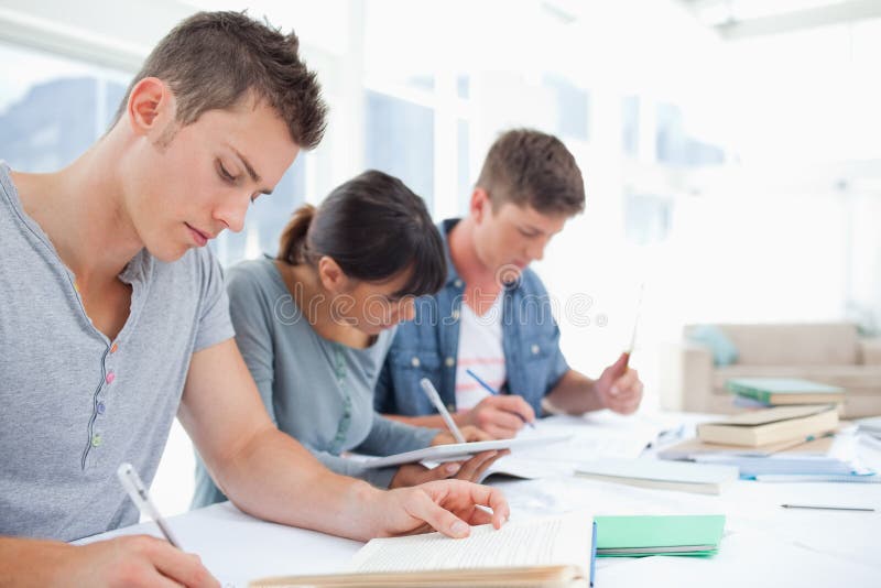 Side View of Three Students Quietly Working Together Stock Photo ...
