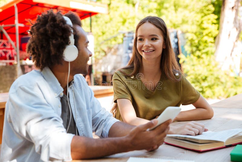 Side View of Two Happy Young Friends Sitting by Table Stock Photo ...
