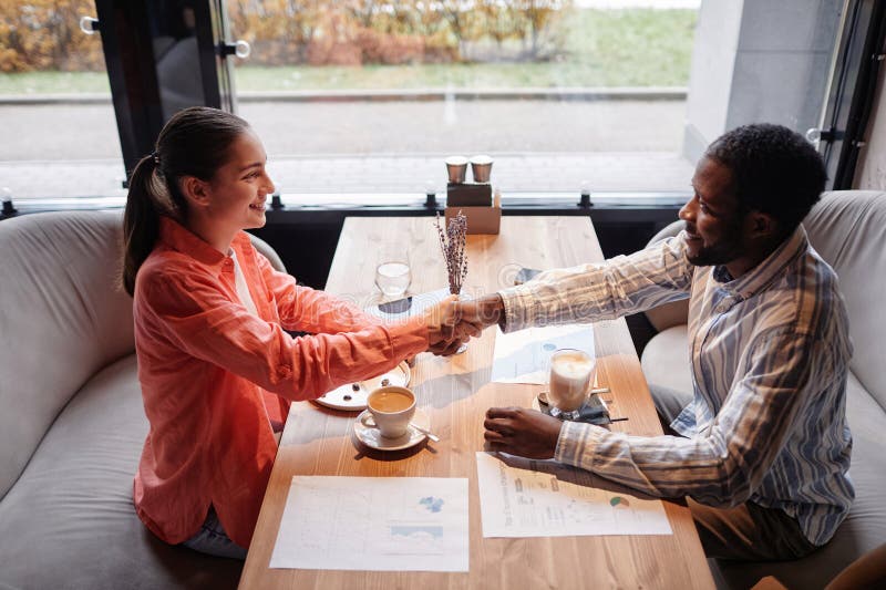 Side View of Two Young Colleagues Greeting One Another by Handshake ...