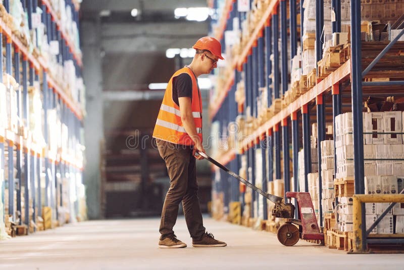 Side View of Warehouse Worker that is in Uniform and Hard Hat Working ...