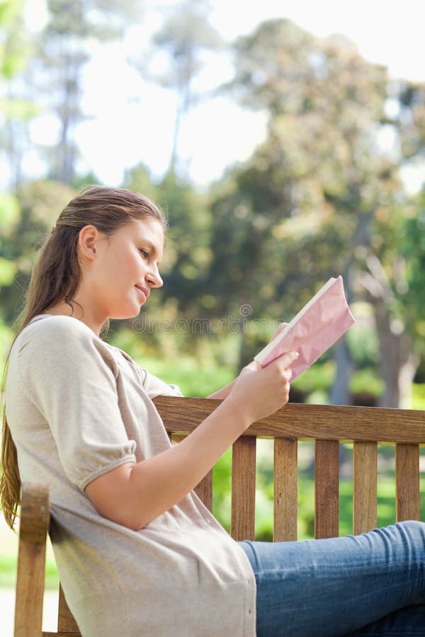 Side View of a Woman Reading a Book on a Park Bench Stock Photo - Image ...