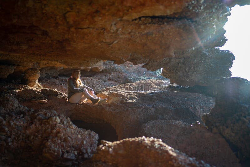 Side View of Woman Sitting on Rock Formation at Beach during Sunset ...