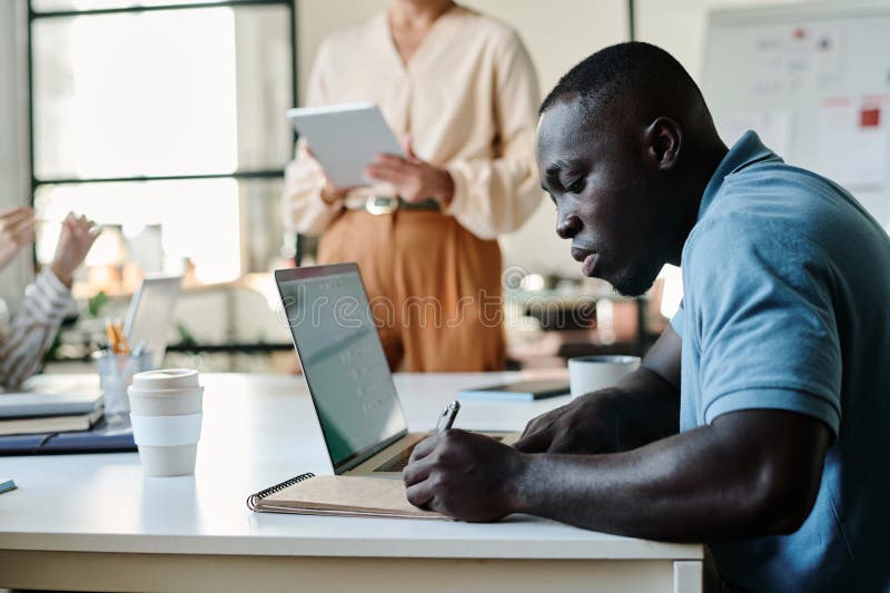 Side View of Young African American Businessman Making Notes in Notepad ...