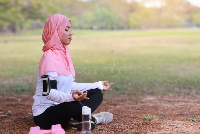 Side View Young Asian Muslim Woman Sitting On Grass Enjoying