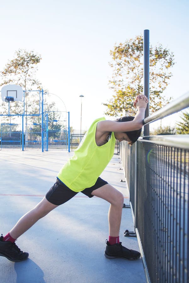 Side View of a Young Basketball Player Stretching Legs before Playing ...