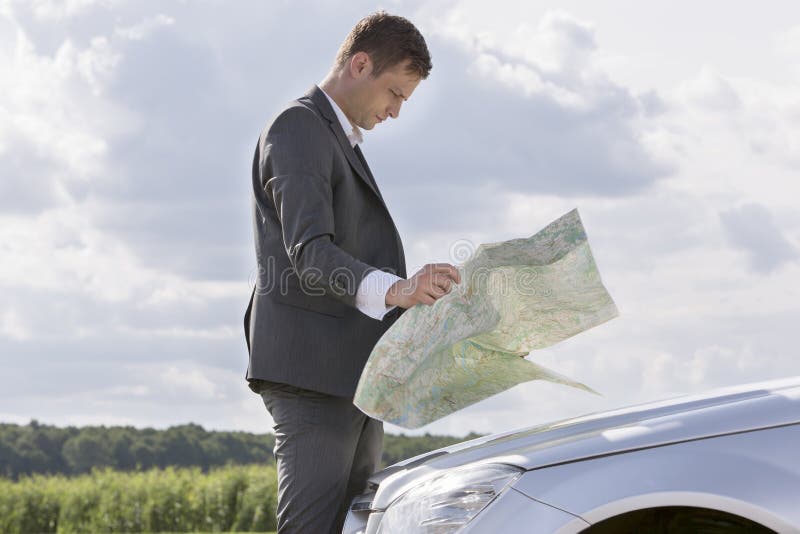 Side View of Young Businessman Reading Map by Car at Countryside Stock ...