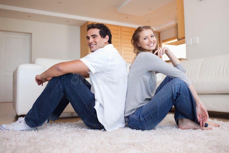 Side View of Young Couple Sitting on the Floor Back-to-back Stock Image ...