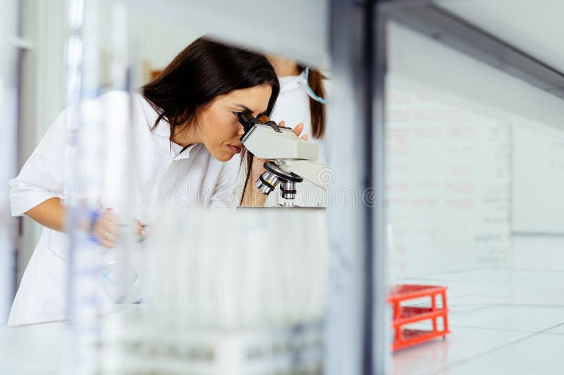 Side View of Young Female Scientist Looking through Microscope. Stock ...