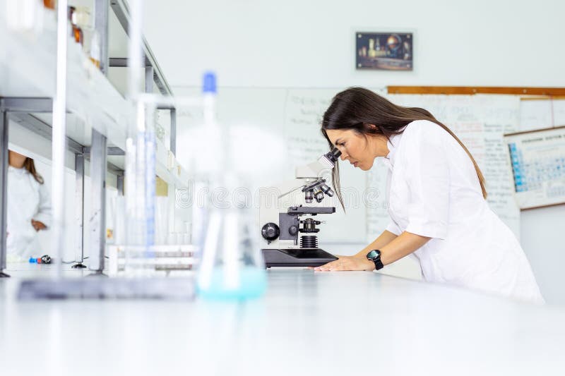 Side View of Young Female Scientist Looking through Microscope. Stock ...