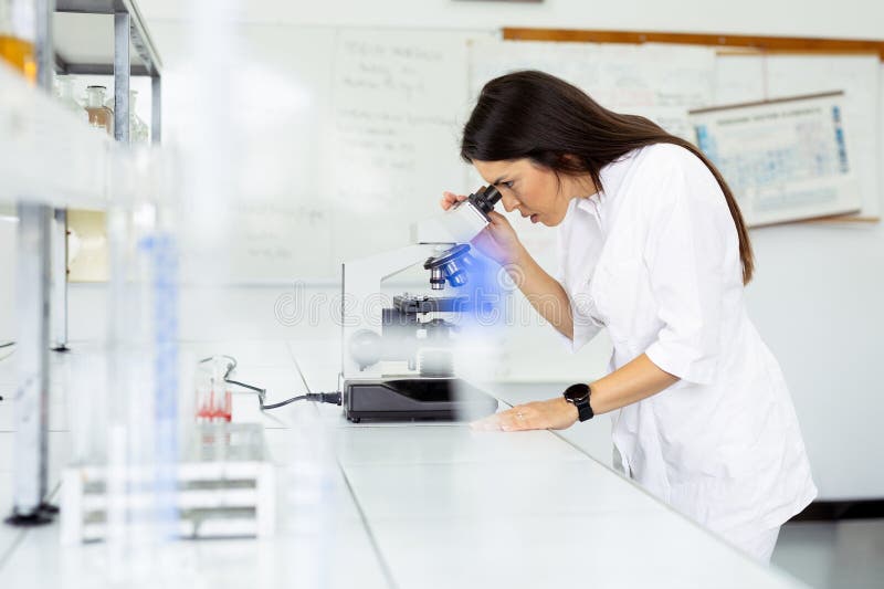 Side View of Young Female Scientist Looking through Microscope. Stock ...