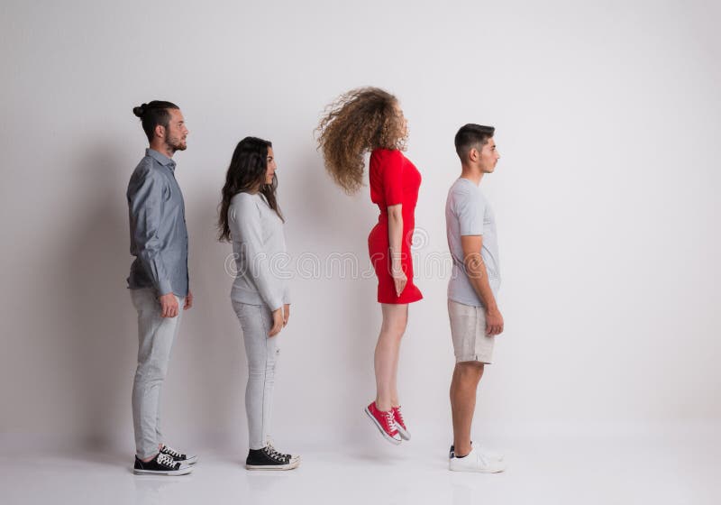 Side View of Young Group of Friends Standing in a Studio, One is ...