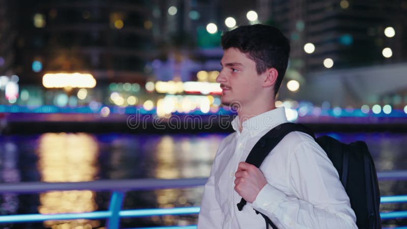 Side View of the Young Guy Walking on a Night Street Wearing a Backpack ...