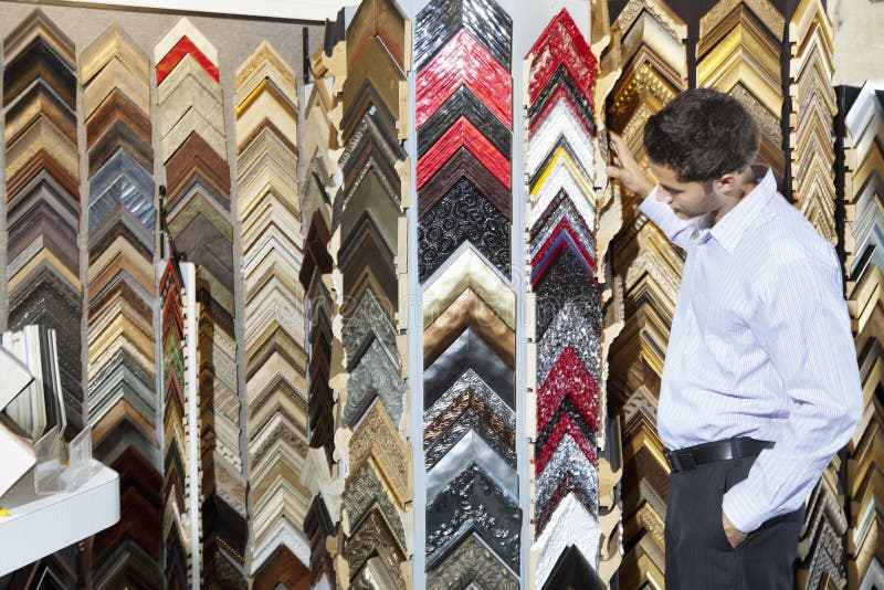 Side View of a Young Man Browsing at a Frame Store with Hands in ...