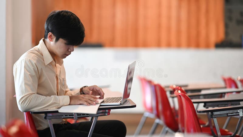 Side View of a Young Man College Student Using Laptop on Lecture Chair ...