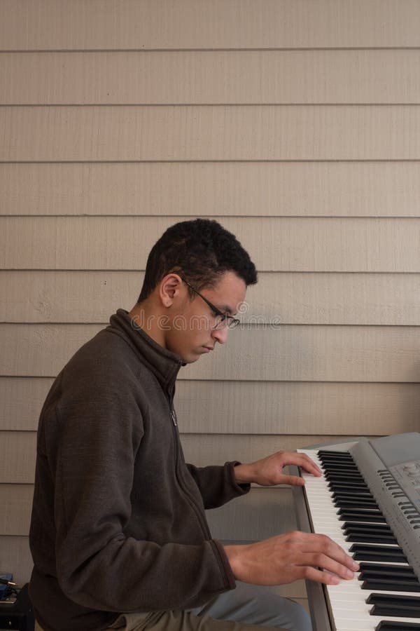 Side View of a Young Man Playing an Electric Keyboard, Hands Wide Apart ...