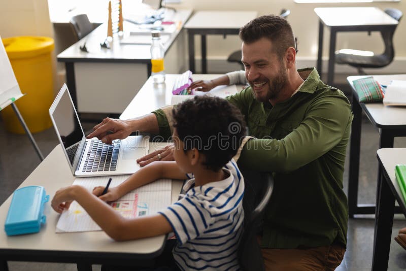 Young School Teacher Helping Boy with Study on Laptop in Classroom ...