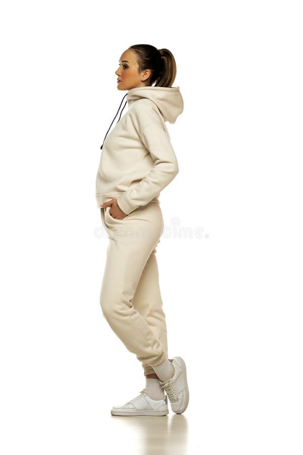 Rear View of a Young Woman in a Beige Tracksuit Posing To a White ...