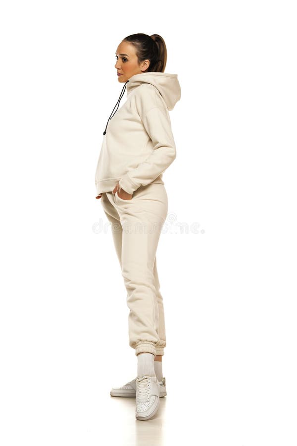 Rear View of a Young Woman in a Beige Tracksuit Posing To a White ...
