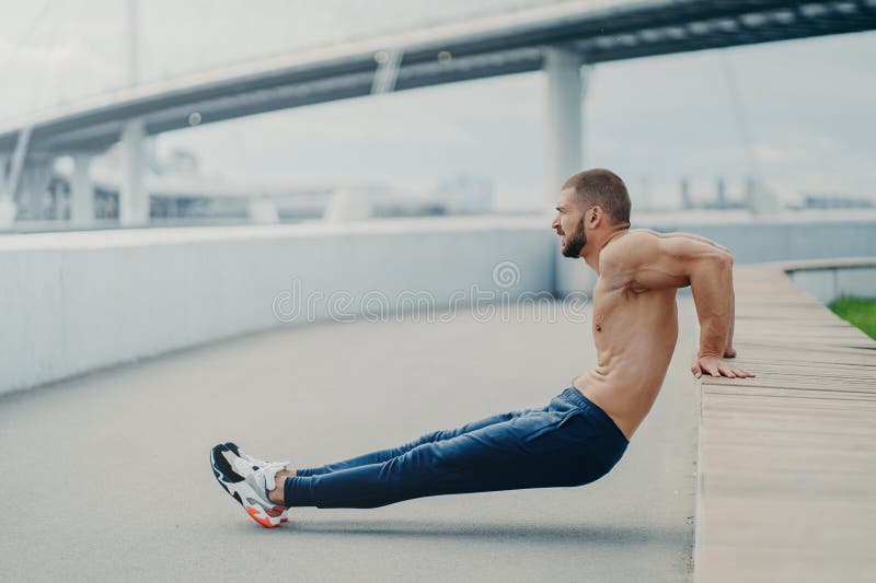 Sideways Shot of Muscular Man Does Reverse Push Up Exercise, Trains ...