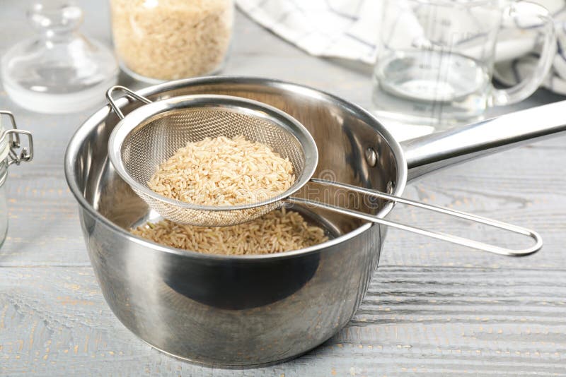 Sieve with Rice in Pot on Grey Wooden Table Stock Photo - Image of ...