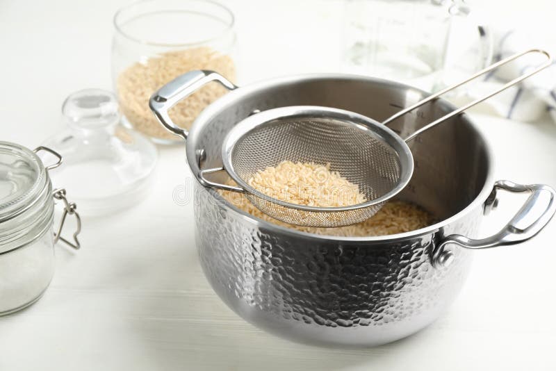 Sieve with Rice in Pot on White Wooden Table Stock Photo - Image of ...