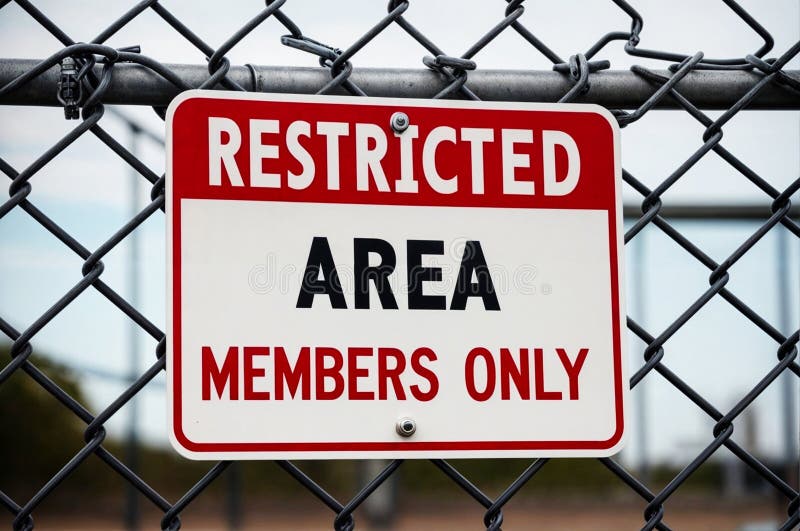 A Sign on a Chain Link Fence with the Text Word "Restricted Area" and ...