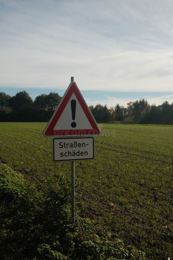 A Sign in a Field with a Red and White Triangle Stock Image - Image of ...