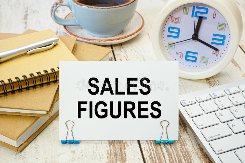 A Sign with the Inscription Sales Figures on the Table with Coffee and ...