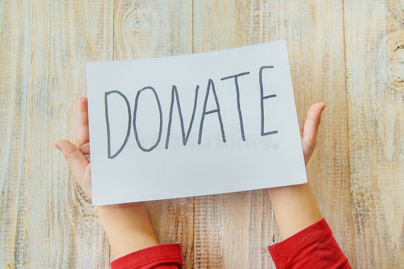 Sign with a Text for a Donation in the Hands of a Child. Selective ...