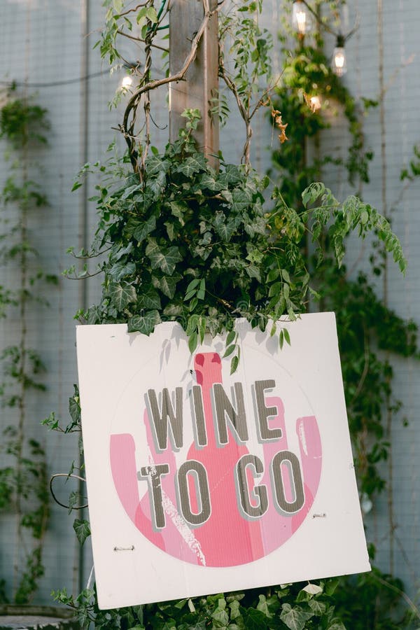 Sign for Wine To Go with Greenery in a Lively Outdoor Setting during ...