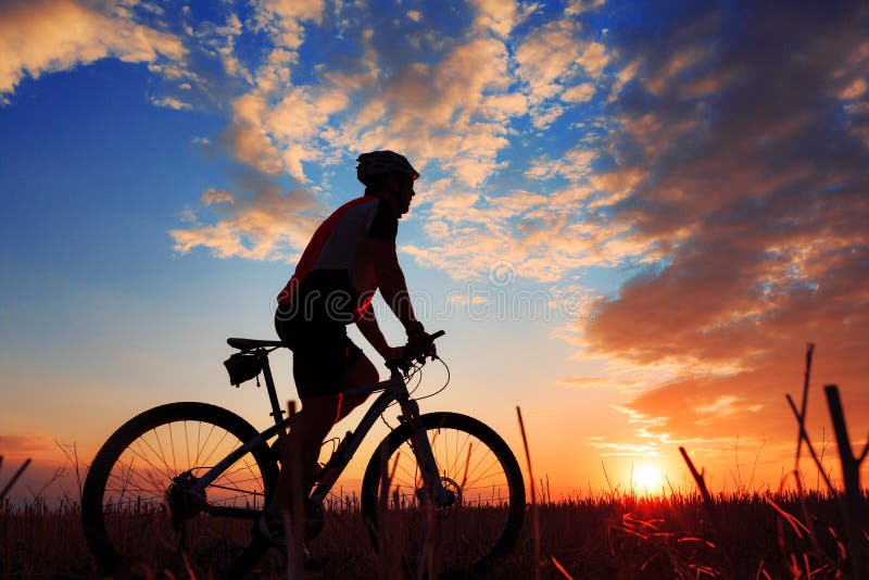Silhouette of a Biker and Bicycle on Sunset Background. Stock Image ...