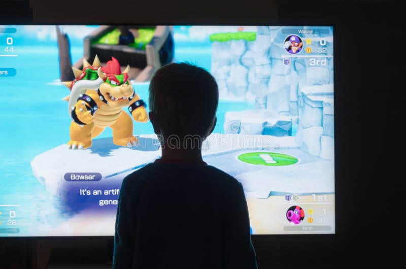 Silhouette of a Boy Standing in Front of a Large TV Screen Watching the ...