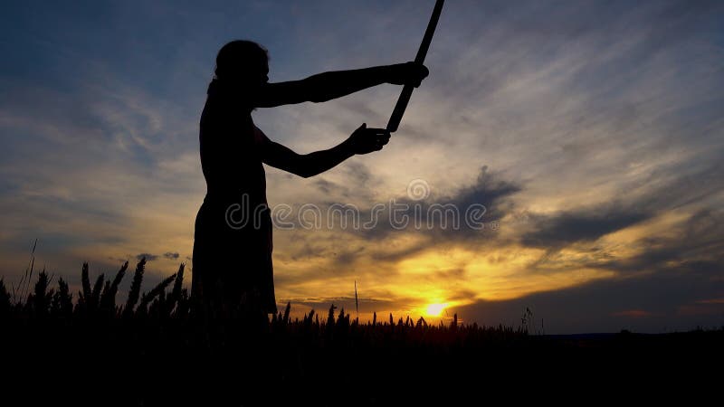 Silhouette of a Boy Training with a Samurai Sword at Sunset. Stock ...