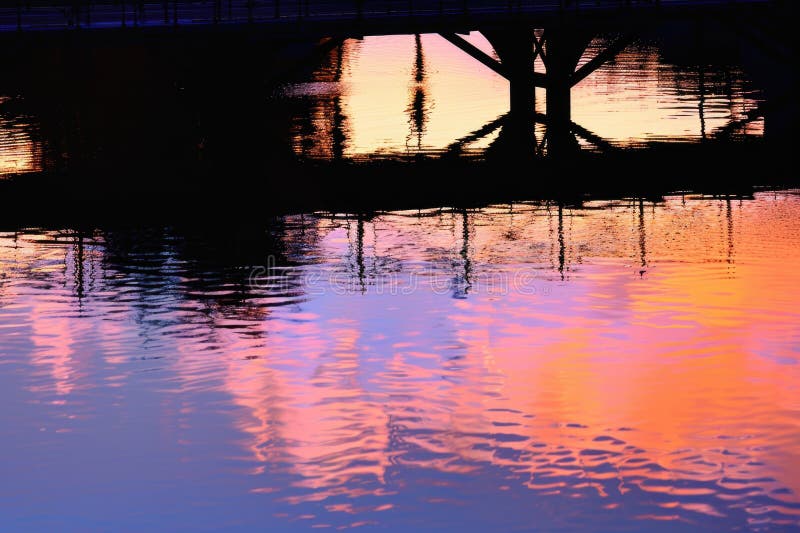 The Silhouette of a Bridge is Reflected in the Still Water, Creating a ...