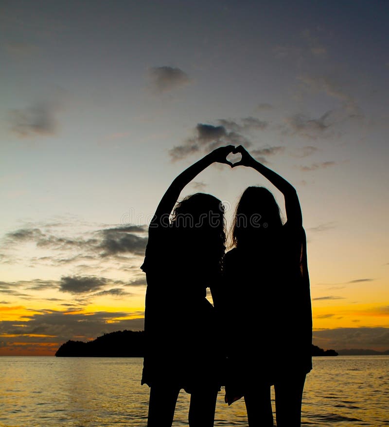 Silhouette De Deux Soeurs Faisant Le Symbole De Coeur Image Stock