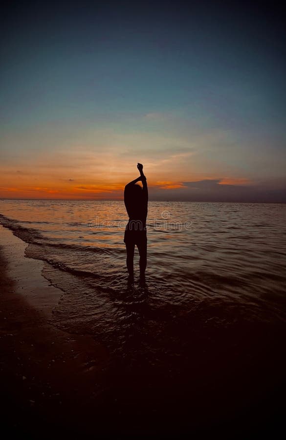 Silhouette of a Female Figure Standing on the Beach at Sunset Stock ...