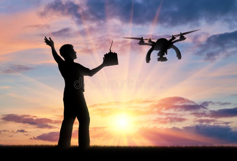 Silhouette of a Flying Drone, and a Man with a Remote Control at Sunset ...